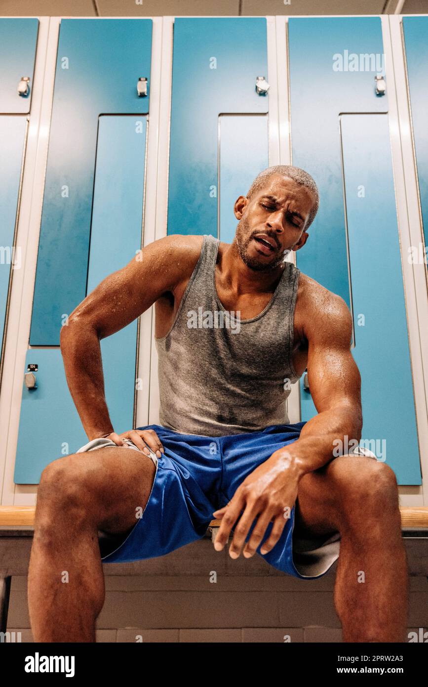 Tired male athlete taking rest while sitting in locker room Stock Photo ...