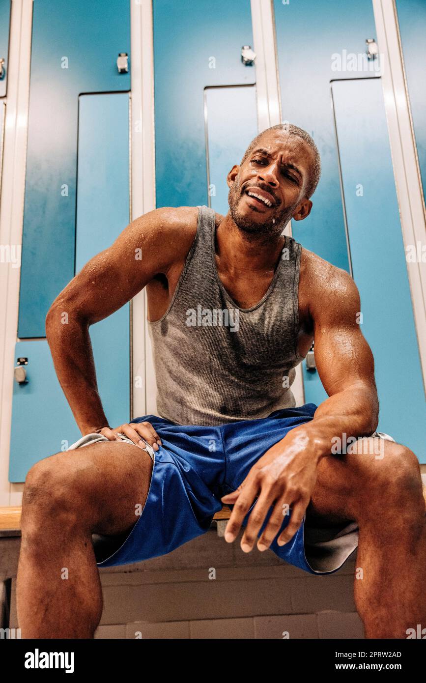Male athlete looking away while sitting in locker room Stock Photo - Alamy