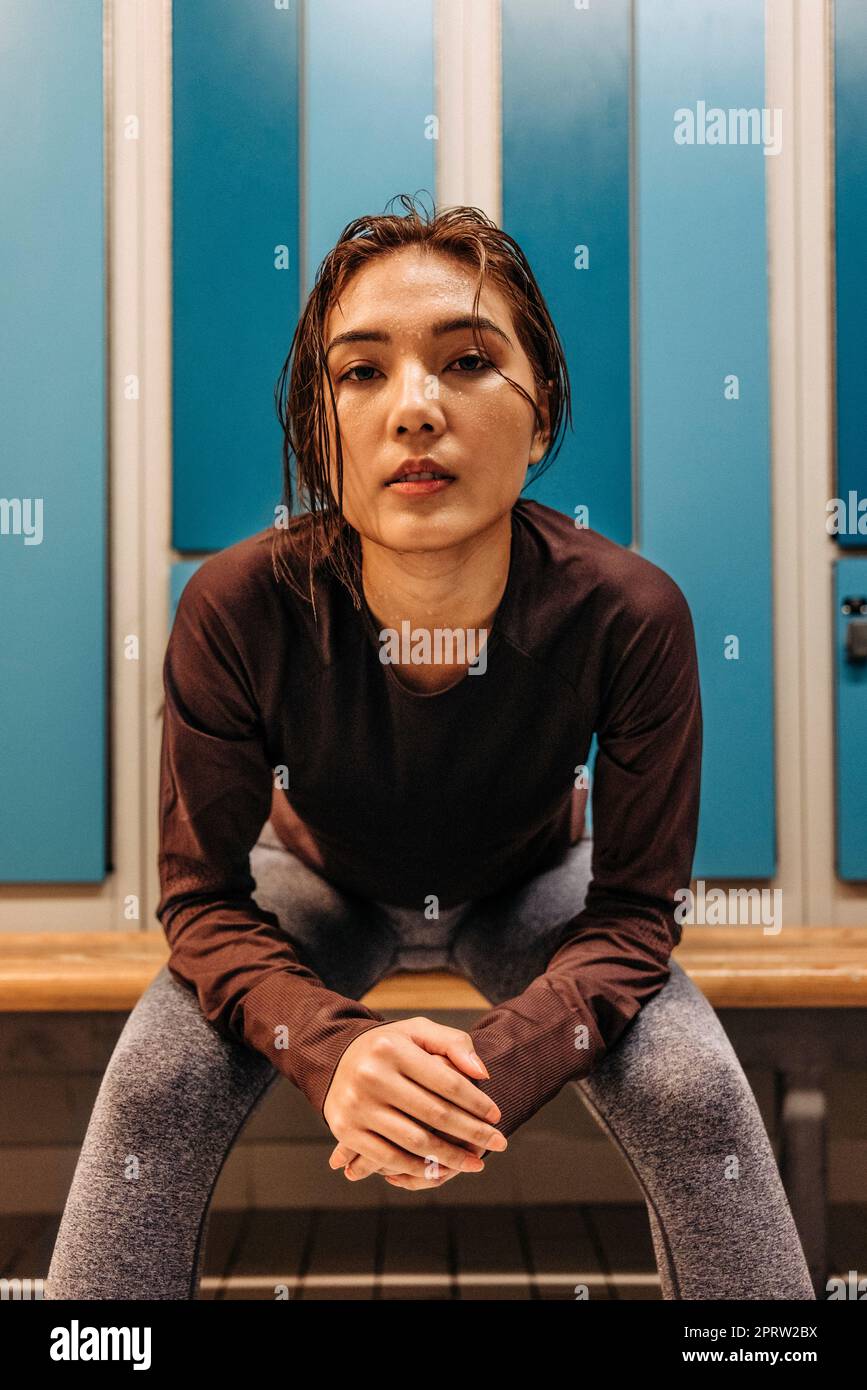 Portrait of confident female athlete sitting in locker room Stock Photo ... Portrait of confident female athlete sitting in locker room Stock Photo ...