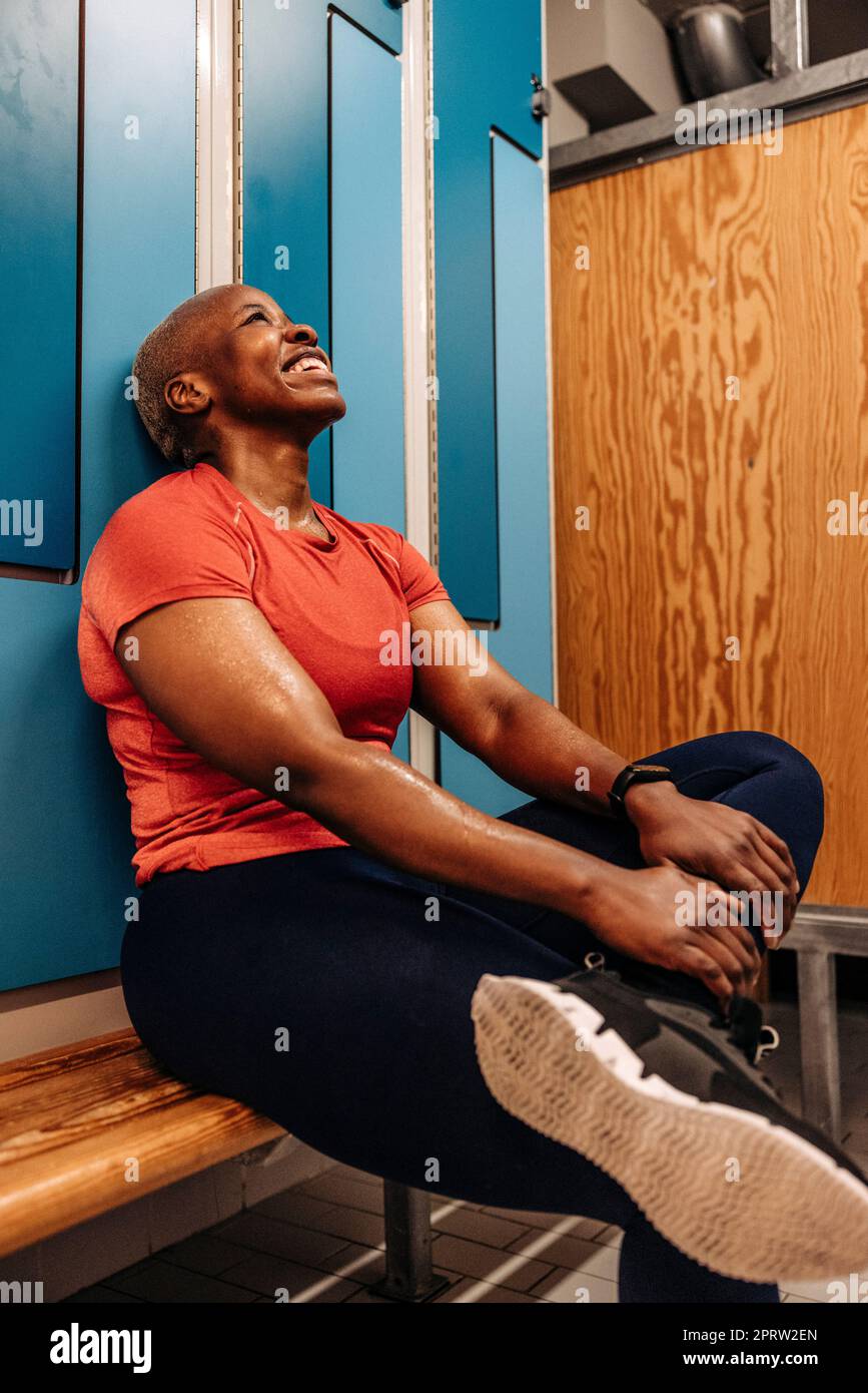 Happy female athlete sitting on bench in locker room Stock Photo - Alamy