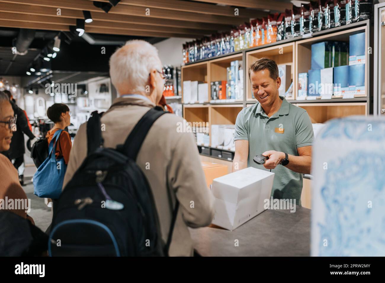 Smiling sales clerk scanning appliance box while customers at checkout ...