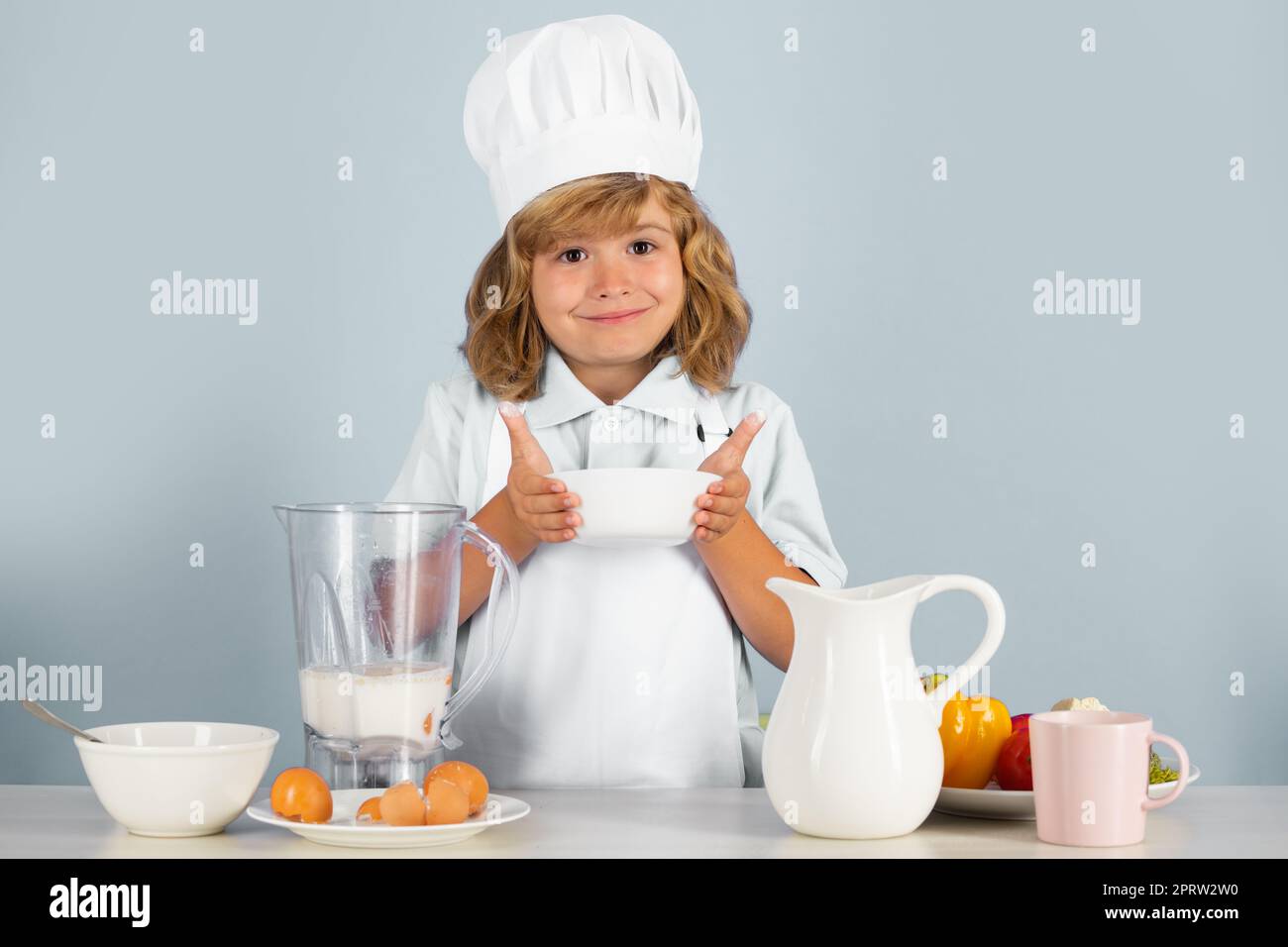 Kid boy in chef hat and apron cooking preparing meal. Little cook with ...