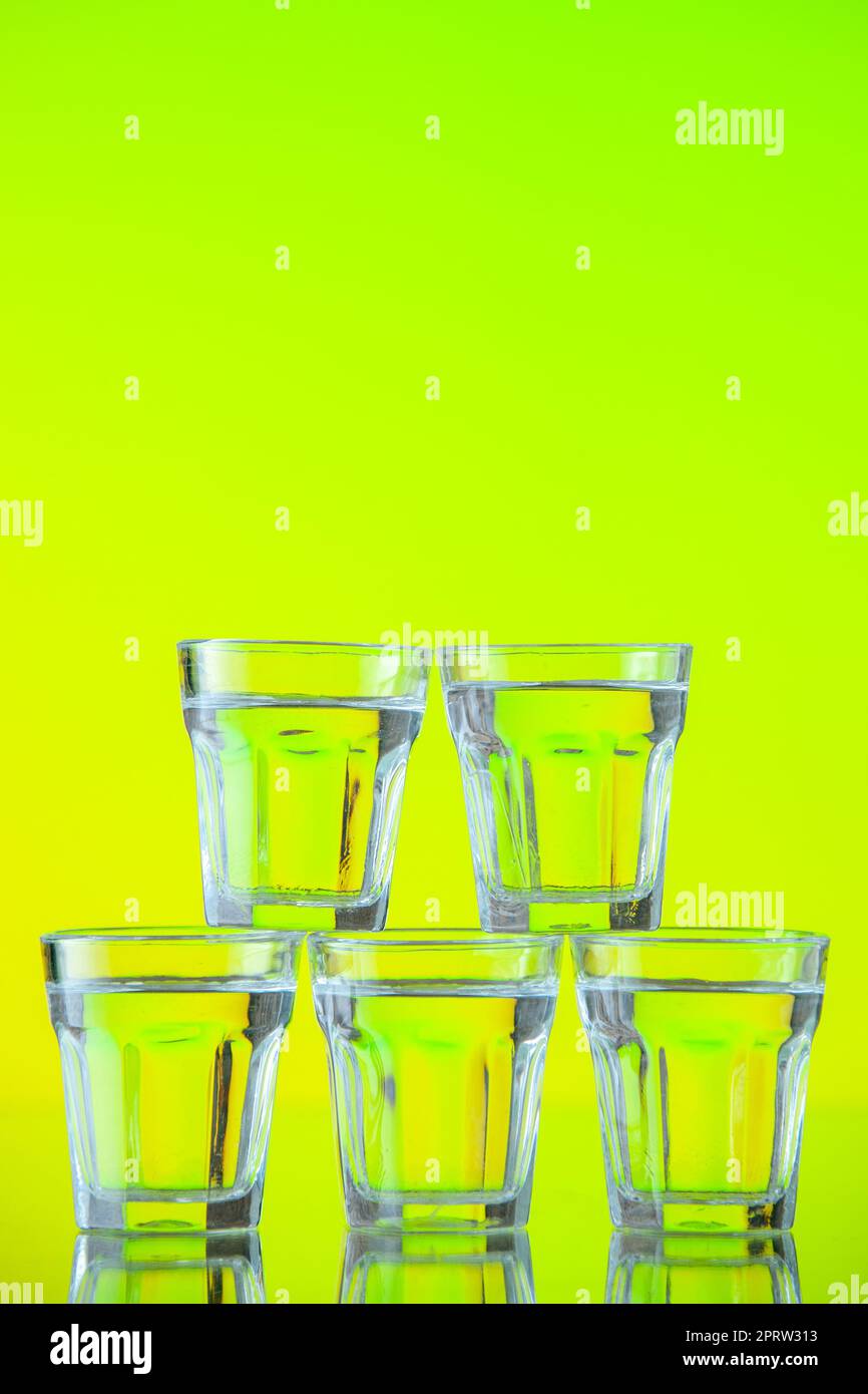 front view water glasses stacked on top of each other on neon green ...