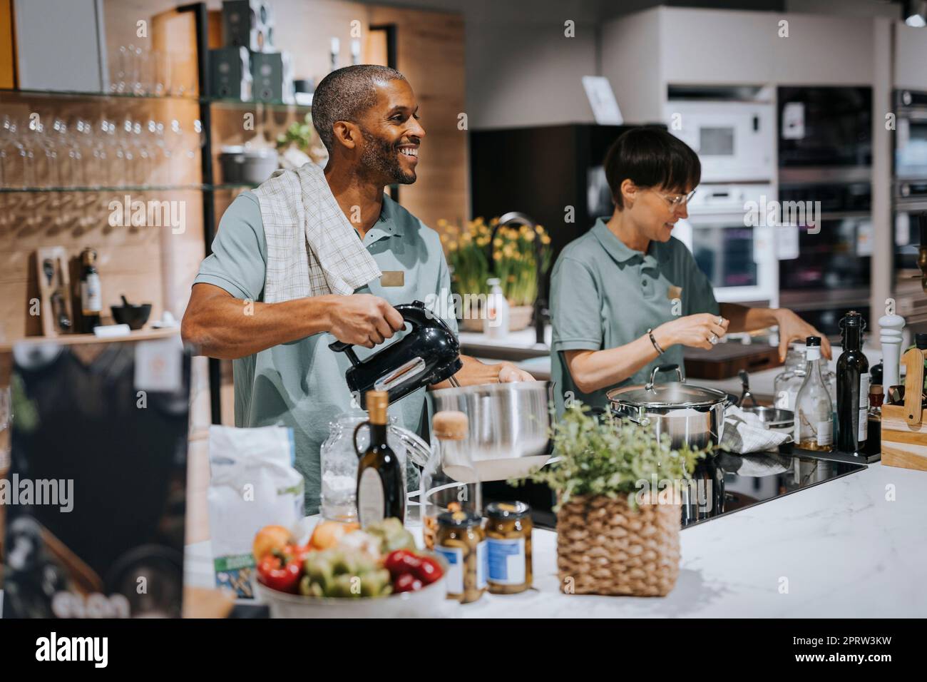 Multiracial male and female colleagues using modern kitchen appliances ...