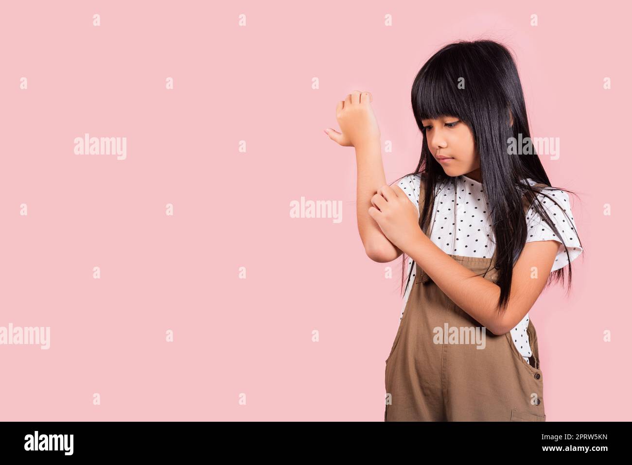 Asian little kid 10 years old scratching itch arm from a mosquito bite ...