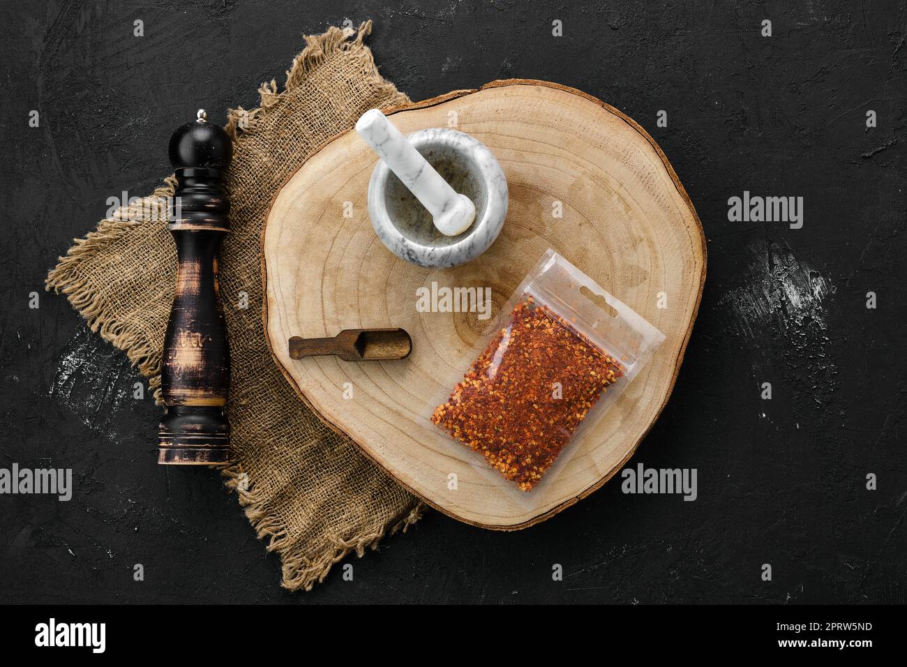 Wooden cross section with chili flakes in plastic package and mortar ...