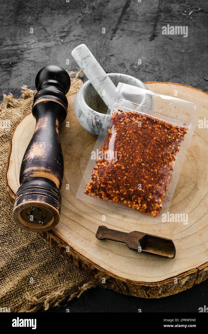 Wooden cross section with chili flakes in plastic package and mortar ...