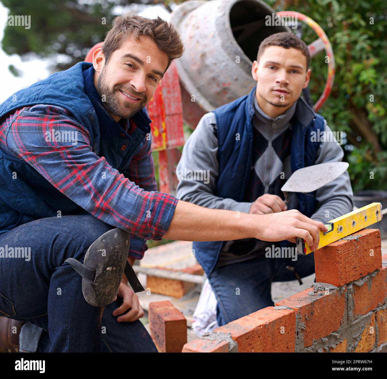 Strong walls and bonds. Portrait of a bricklayer and his apprentice at ...