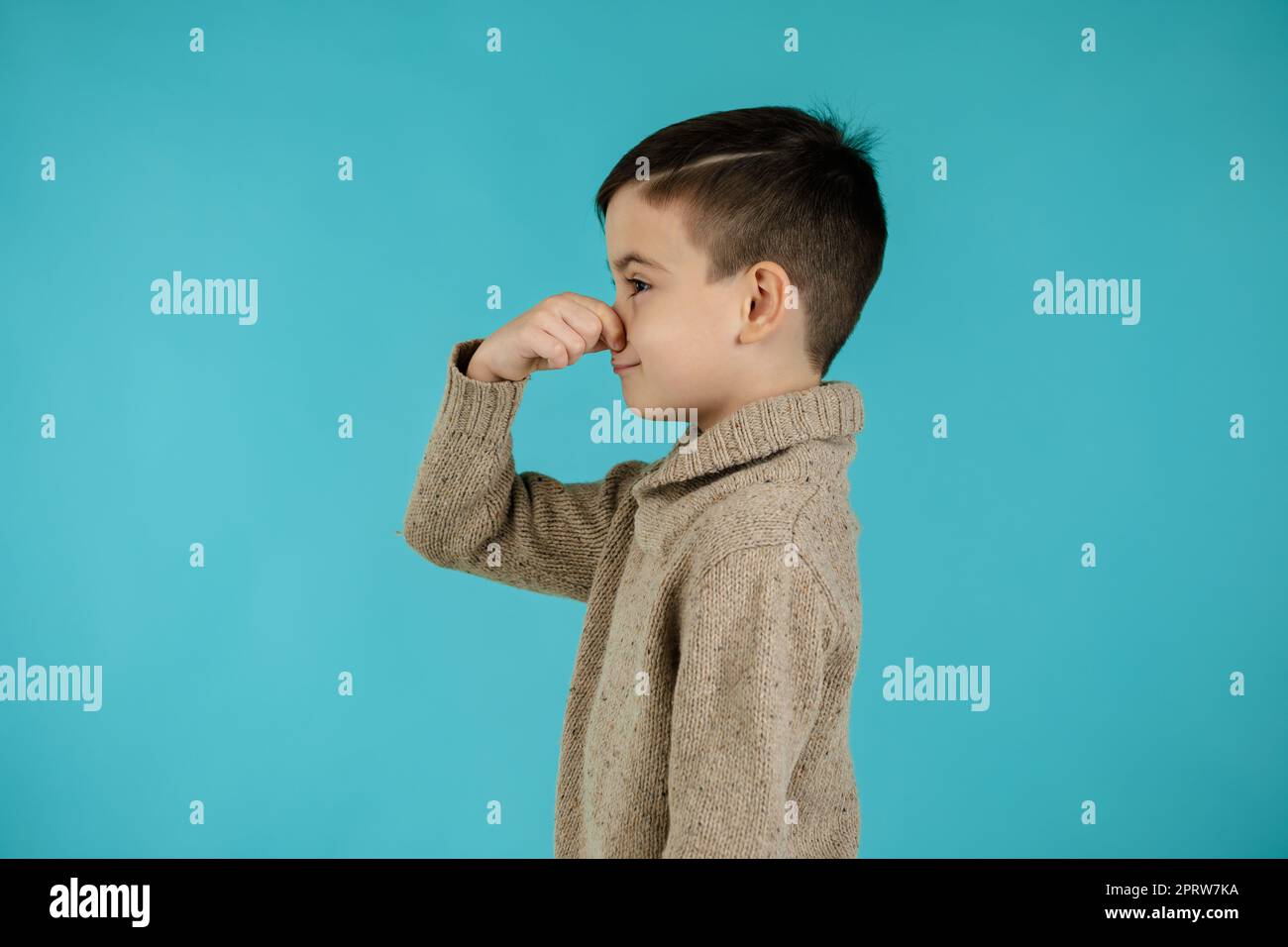 little child boy doing gesture smells bad on blue background. facial ...