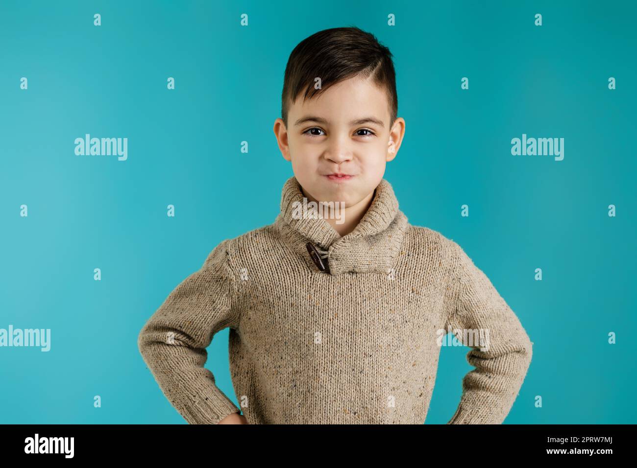 Cute funny little child boy in sweater fooling around on blue ...