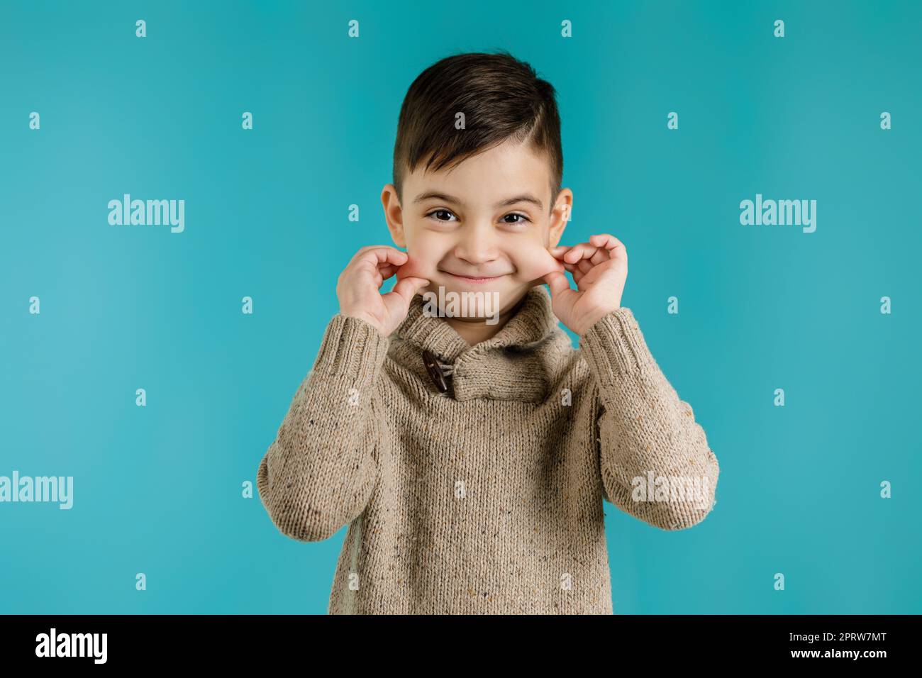 Cute smiling little child boy looking at the camera on blue background ...