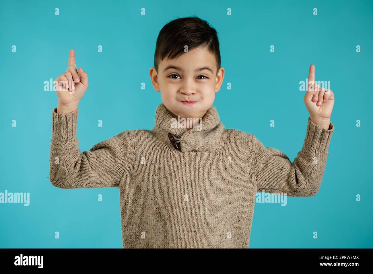 Cute smiling little child boy pointing up and looking at the camera on ...