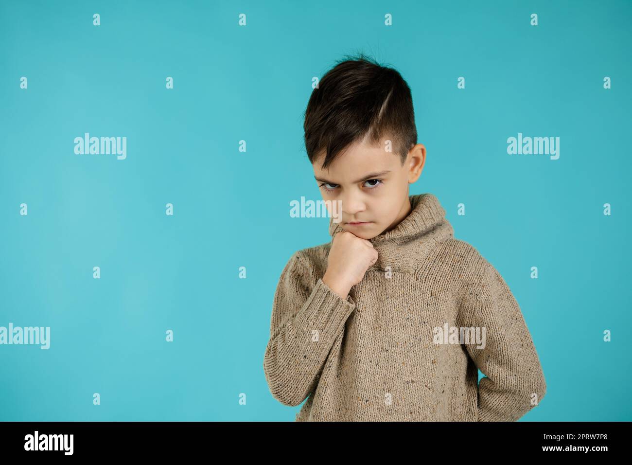 Cute little child boy thinks about something on blue background. Human ...
