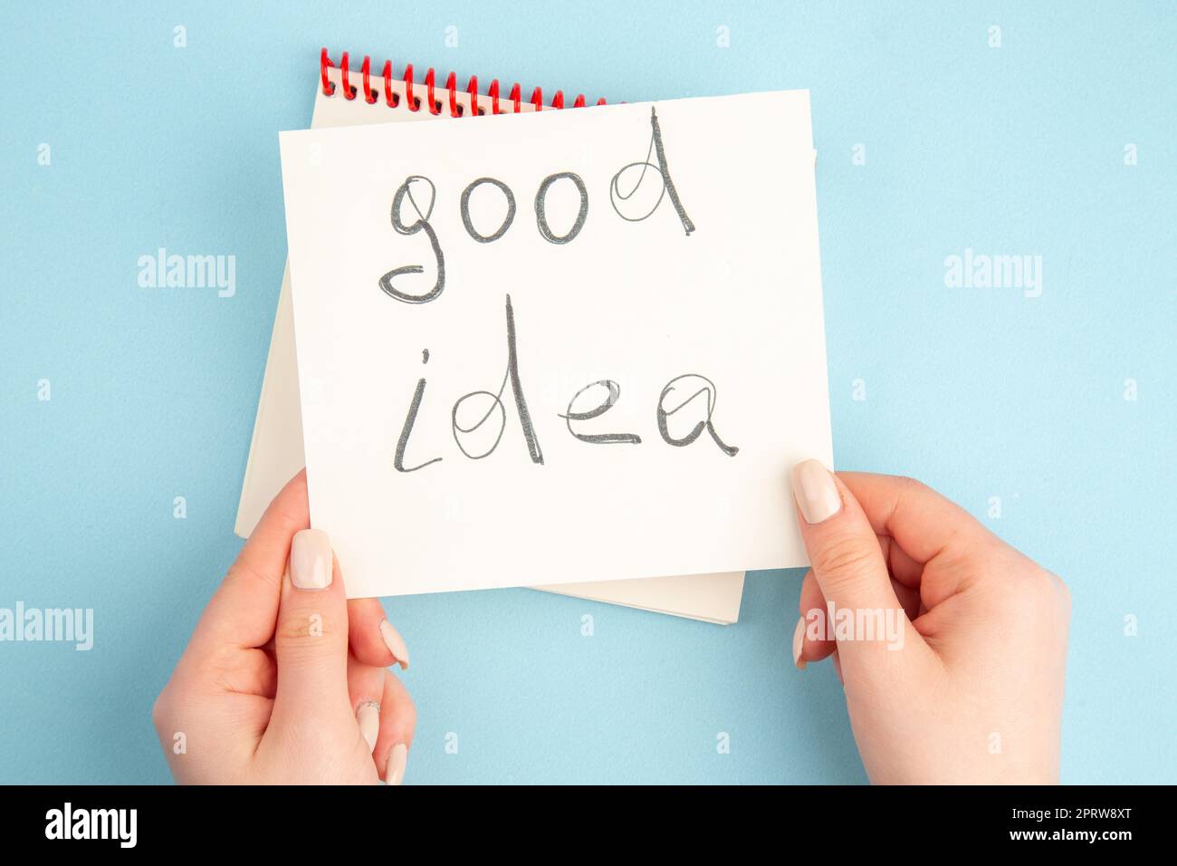 top view good idea written on sticky note in female hands on blue ...