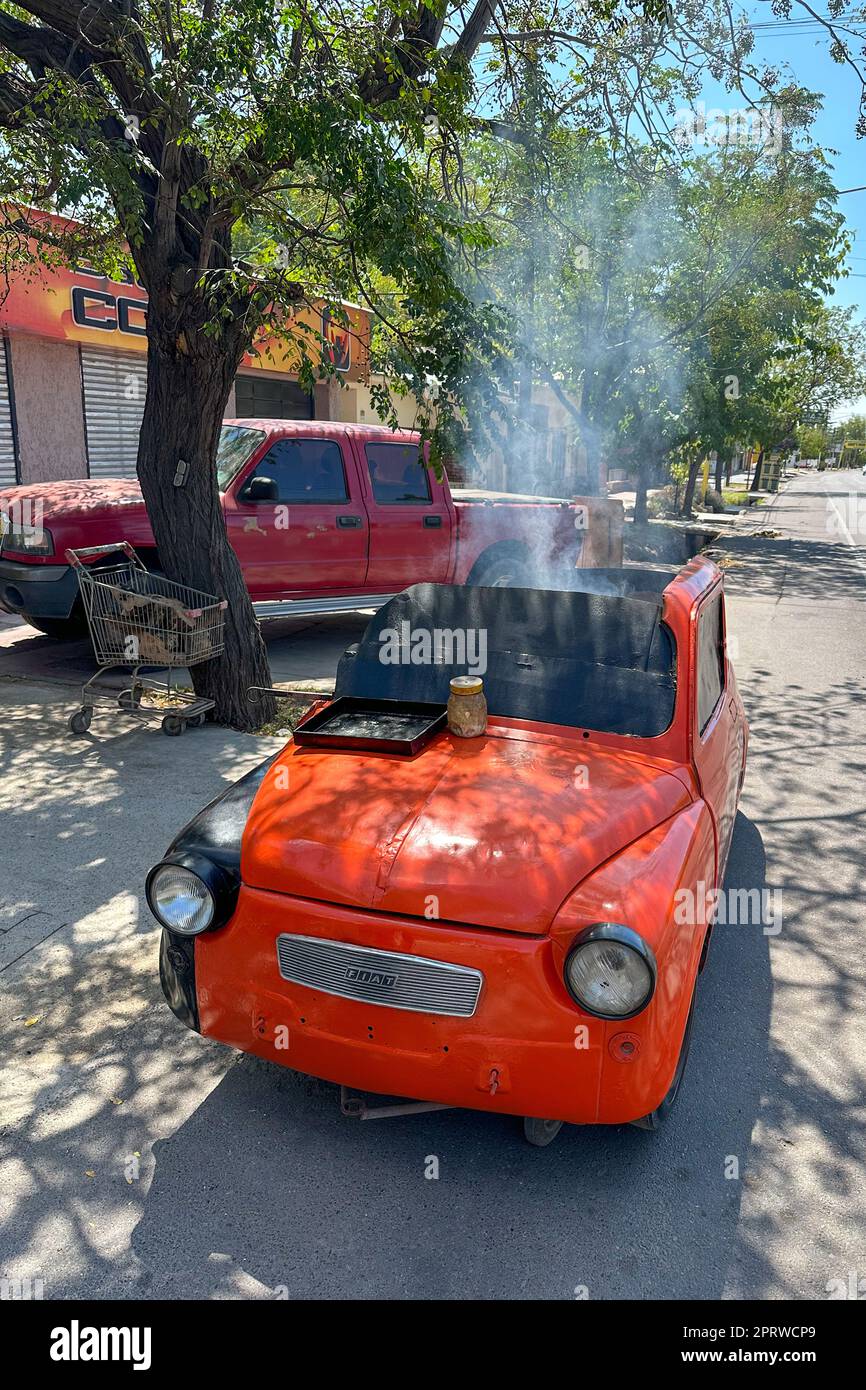 An old car converted into a parrilla or grill, cooking at a restaurant ...
