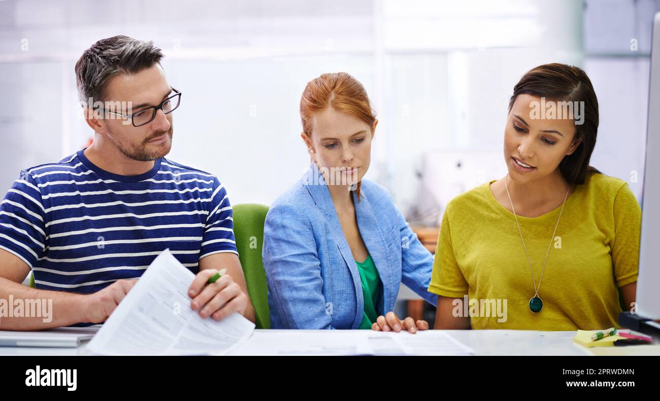 This is puzzling. three colleagues puzzled over some paperwork in an ...