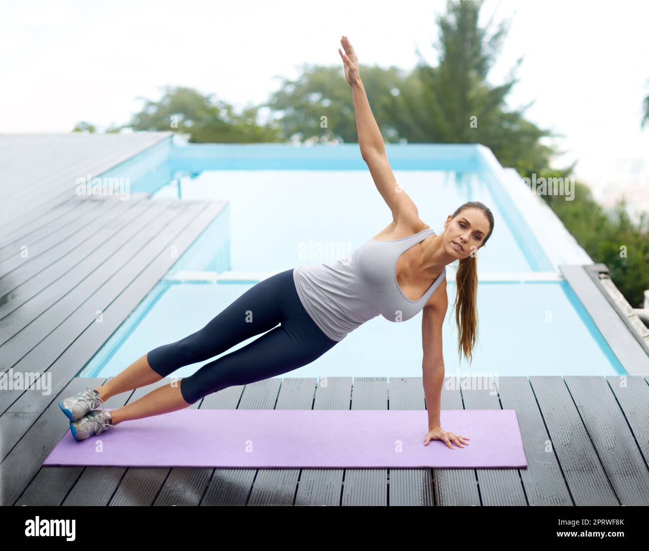 Demonstrating the sidewards plank yoga pose. a gorgeous young woman ...