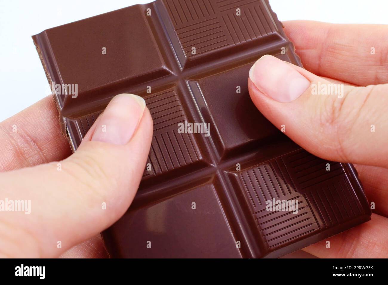 Caucasian woman hands holding and breaking off chocolate from a bar ...