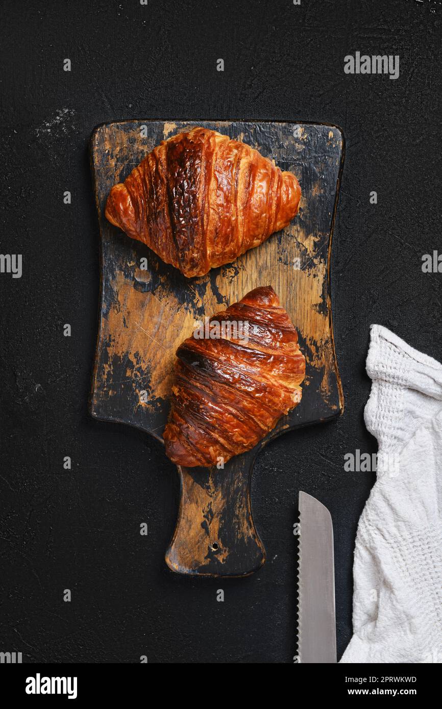 Overhead view of crispy croissant on wooden serving board Stock Photo ...