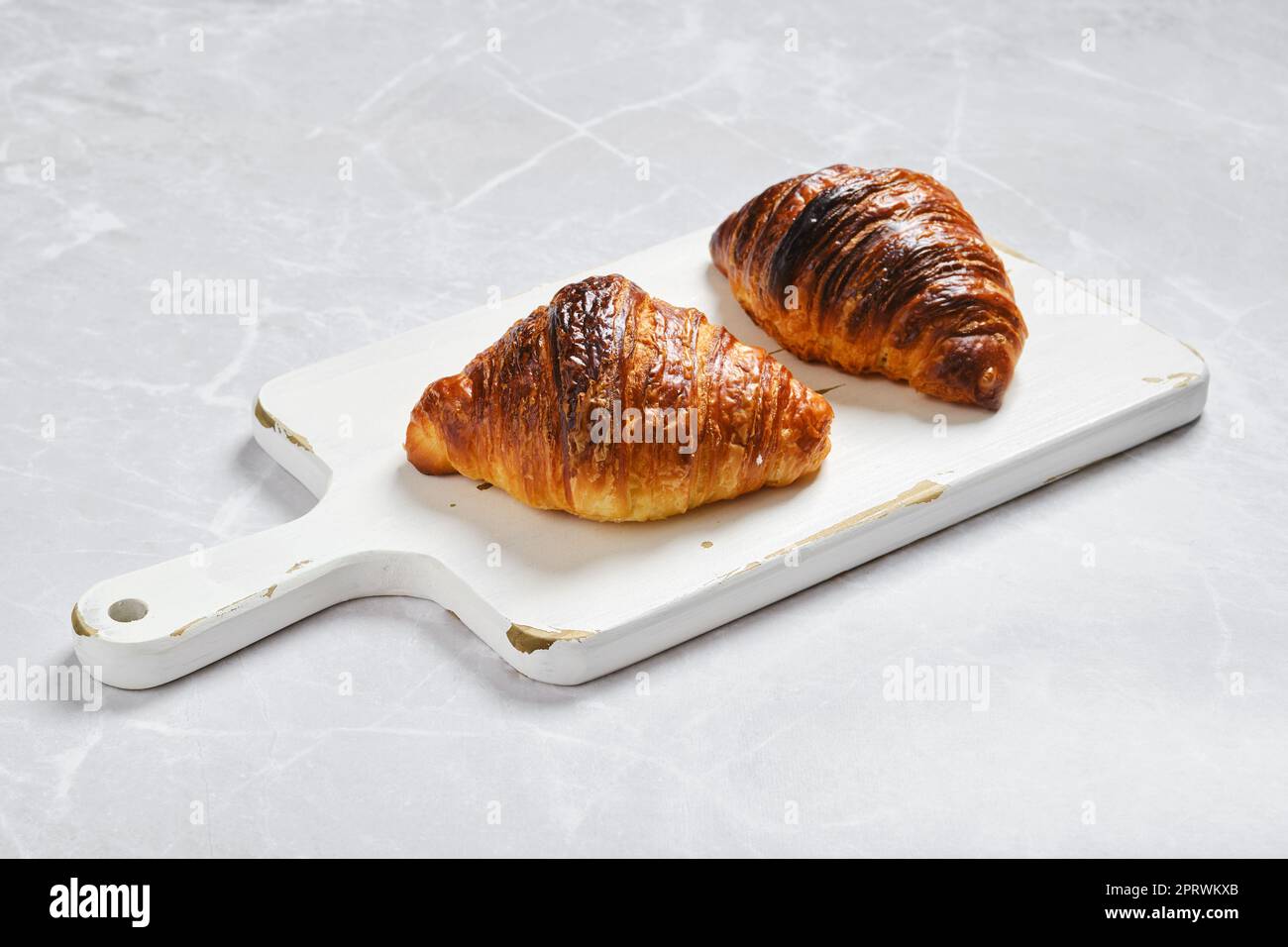 Crispy croissant on serving board on marble background Stock Photo - Alamy
