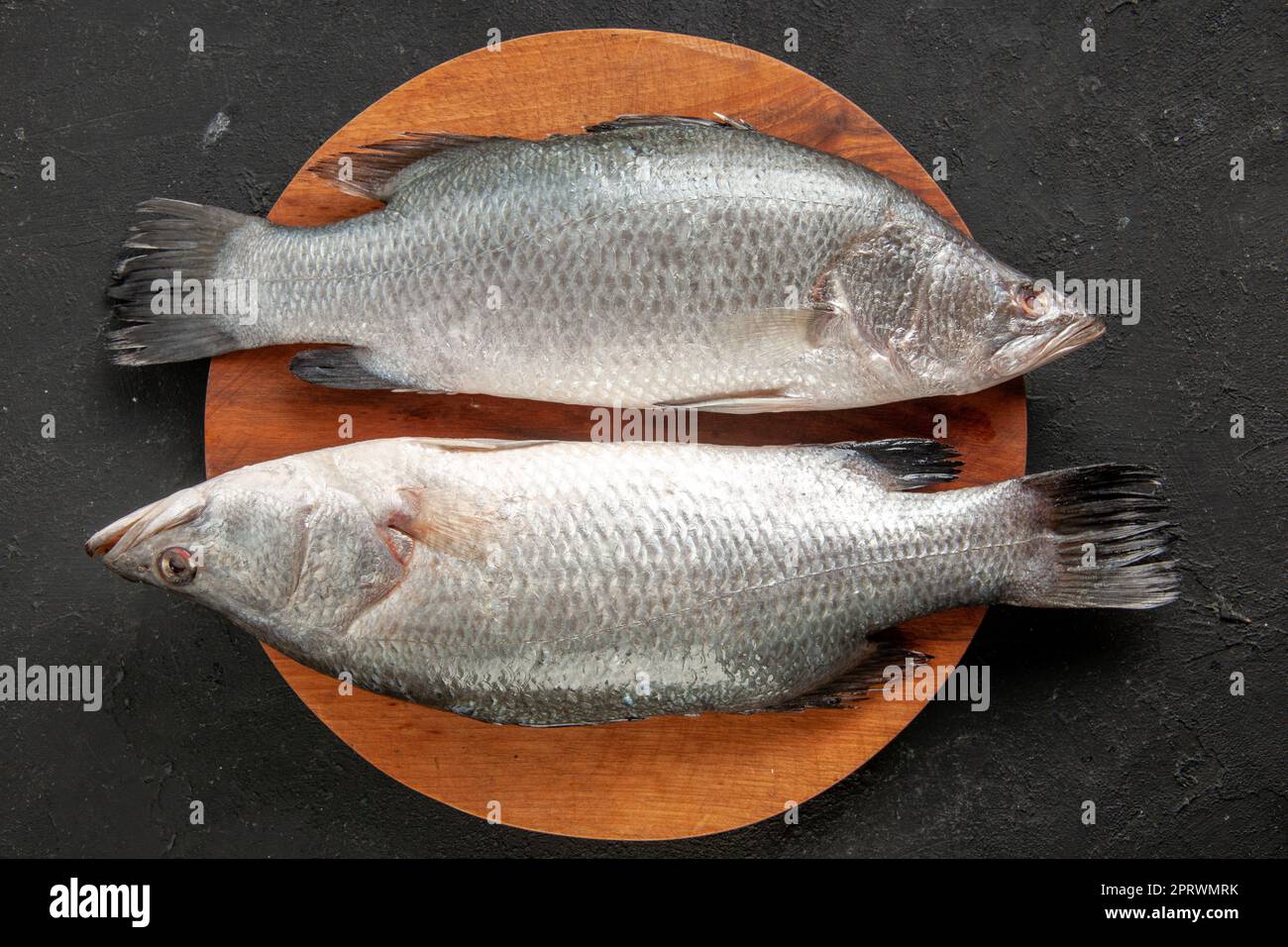 top close view fresh raw fish on round wood board on black table Stock ...