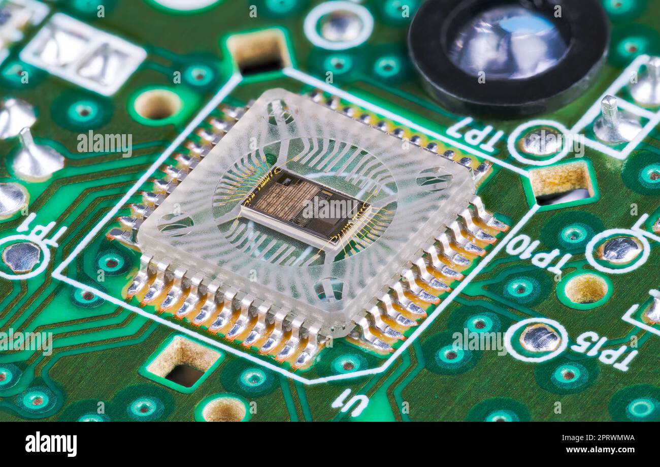 Closeup a microchip die inside optical sensor on green printed circuit board. Electronic square ...