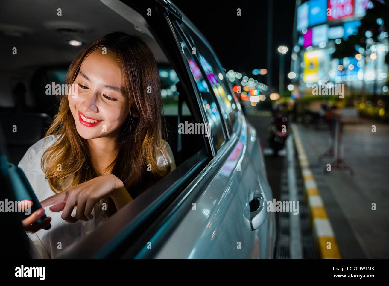 Asian businesswoman commuting from office in Taxi backseat with mobile ...