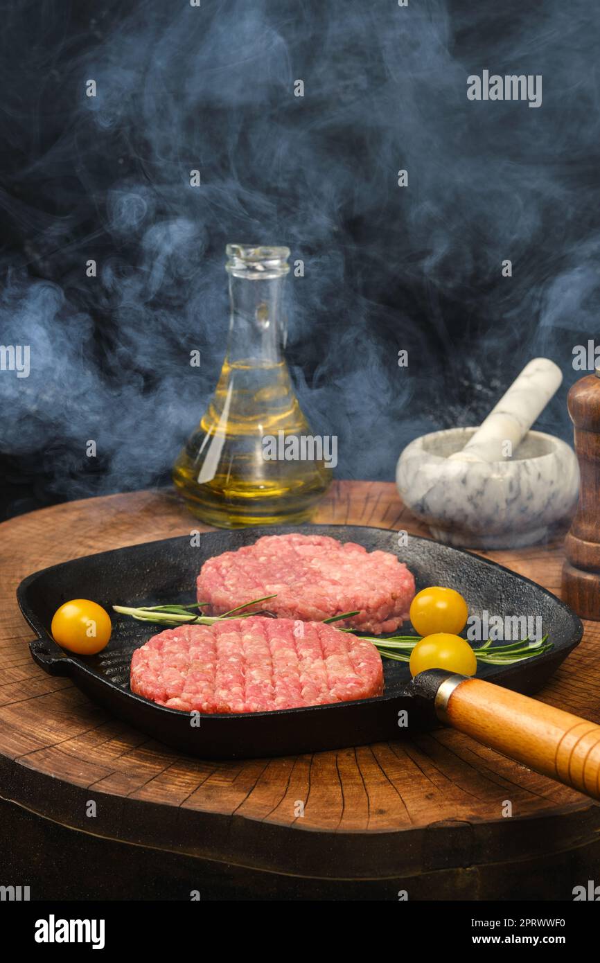 Smoky raw beef burger patty on frying pan Stock Photo - Alamy
