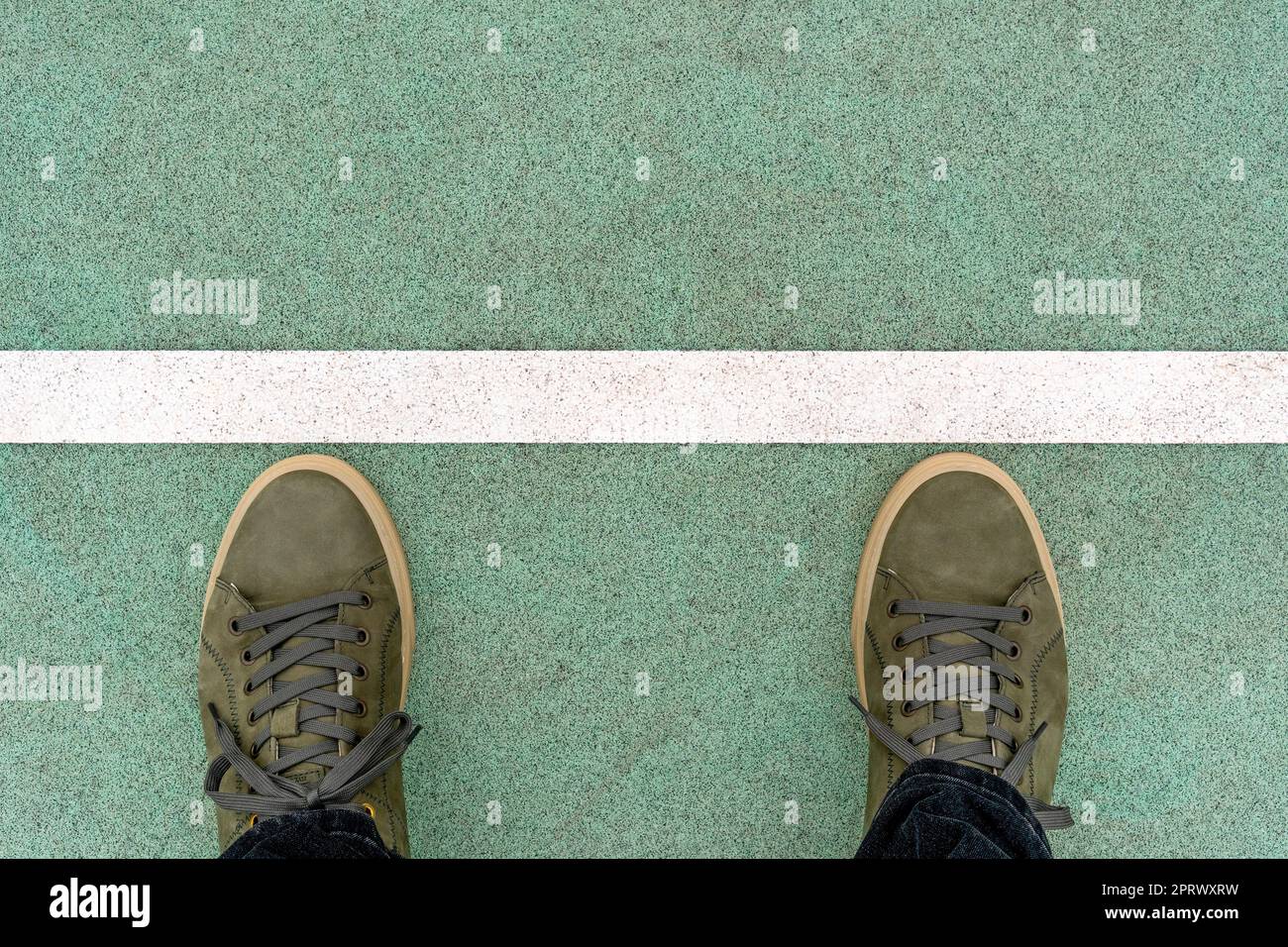 Men feet in green leather sneakers stand on the rubberized track, on a ...