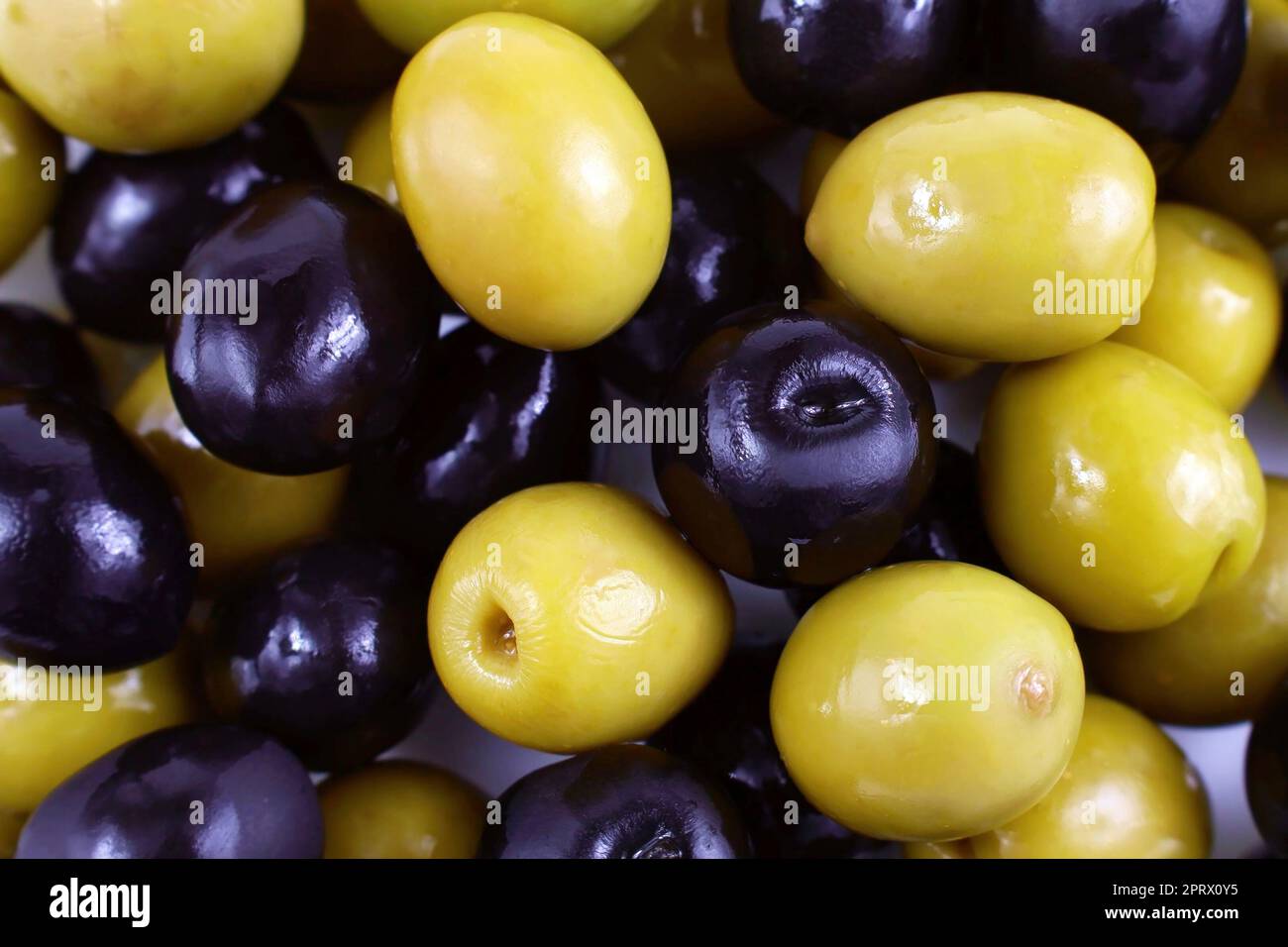 Top view of many green and black marinated whole olives texture close ...