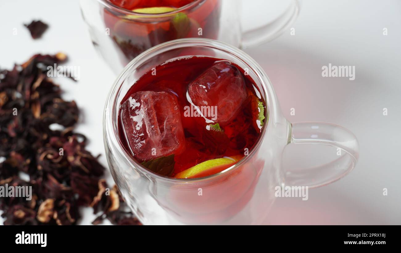 Hibiscus cold tea drink with ice cubes and lemon in glass Stock Photo ...