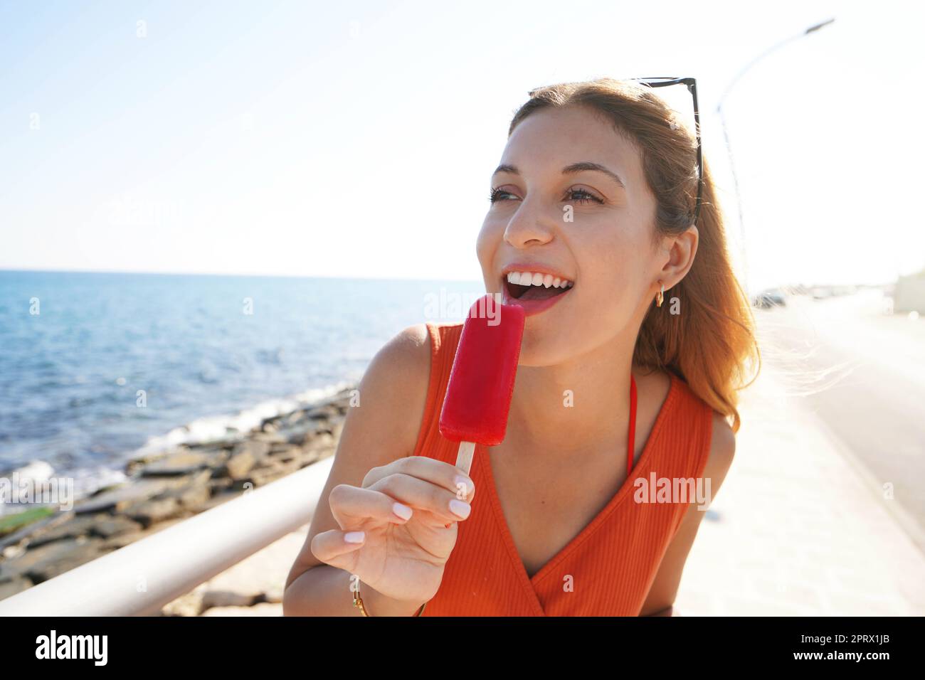 Beautiful Girl Eating A Red Popsicle On Promenade Beach On Summer Stock