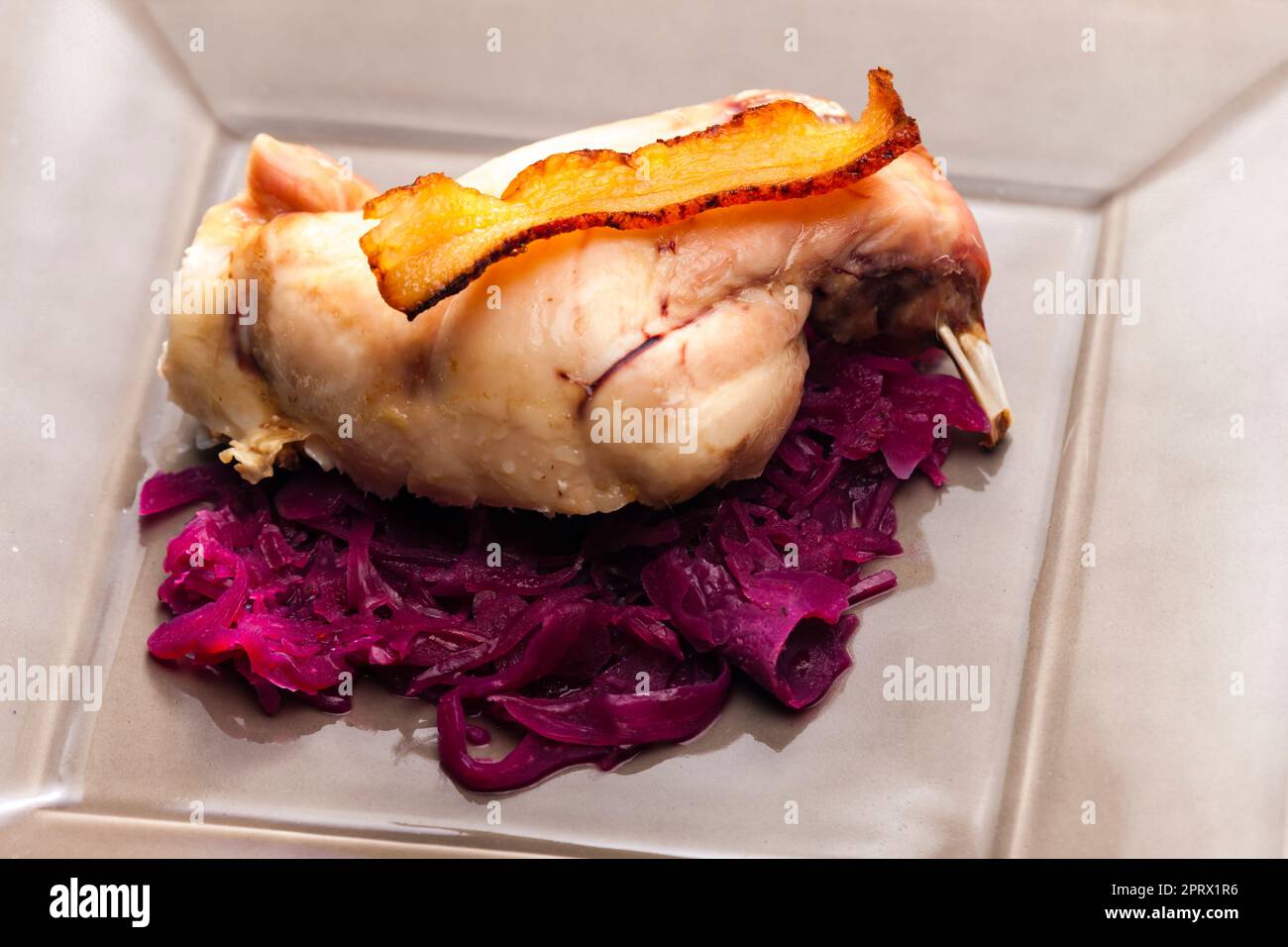 rabbit leg baked with bacon and served with red cabbage Stock Photo - Alamy