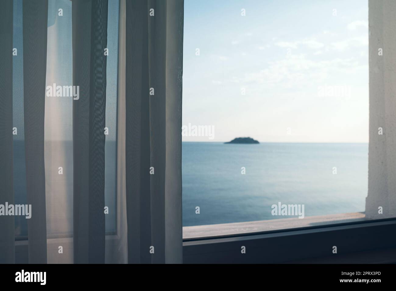 small ocean island seen through a window with transparent fabric ...