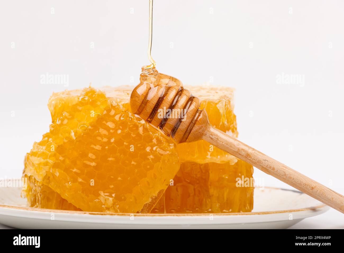 Fresh cut comb honey and wooden dipper on white Stock Photo - Alamy