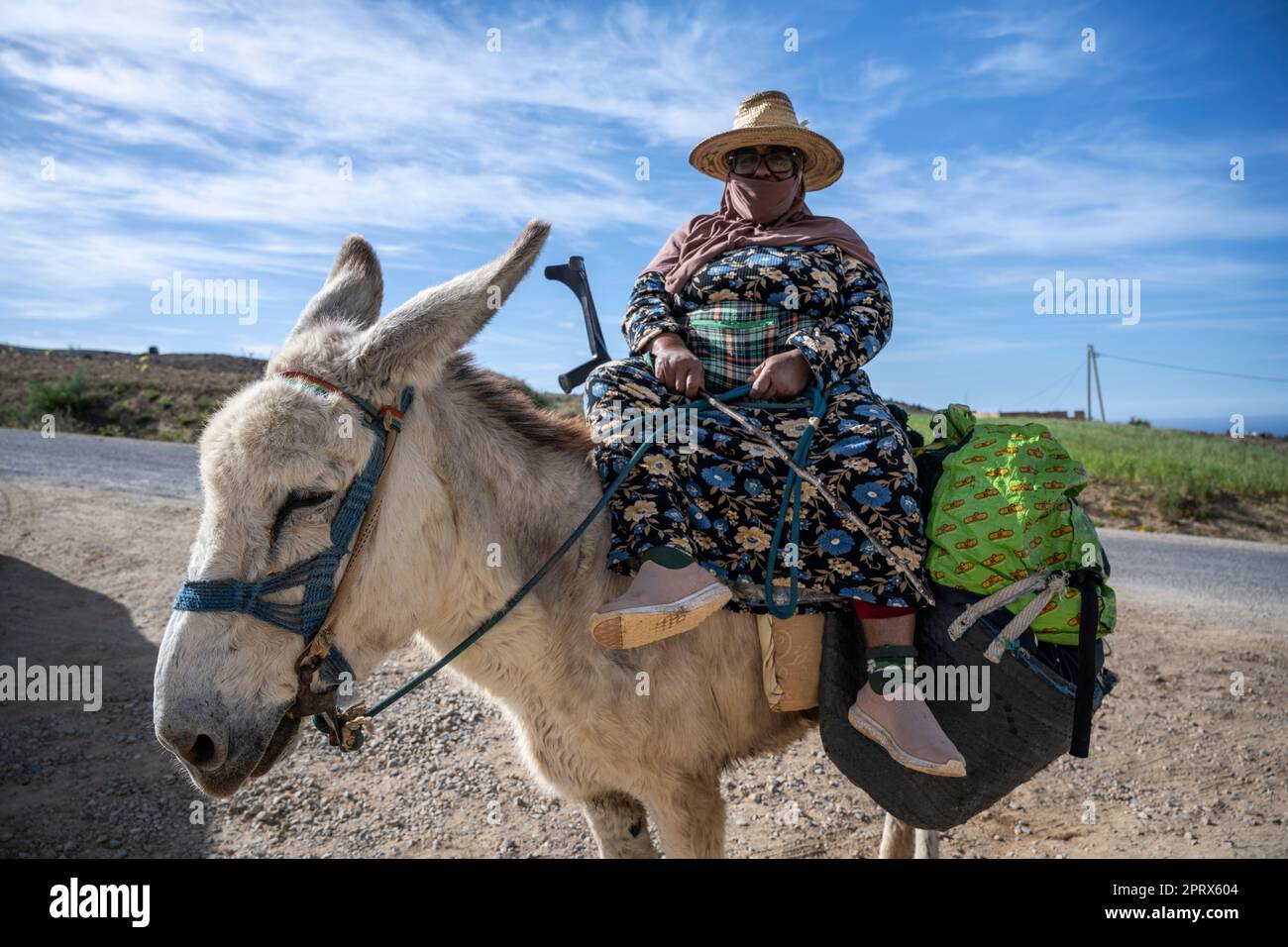 Woman with a straw hat and crutches riding a mule Stock Photo - Alamy