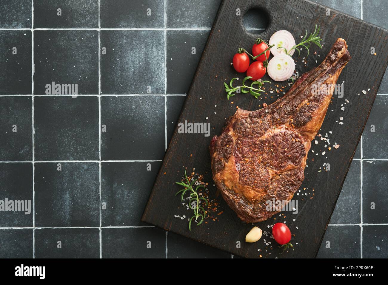 Tomahawk steak. Sliced grilled tomahawk beef steak with baked cherry ...