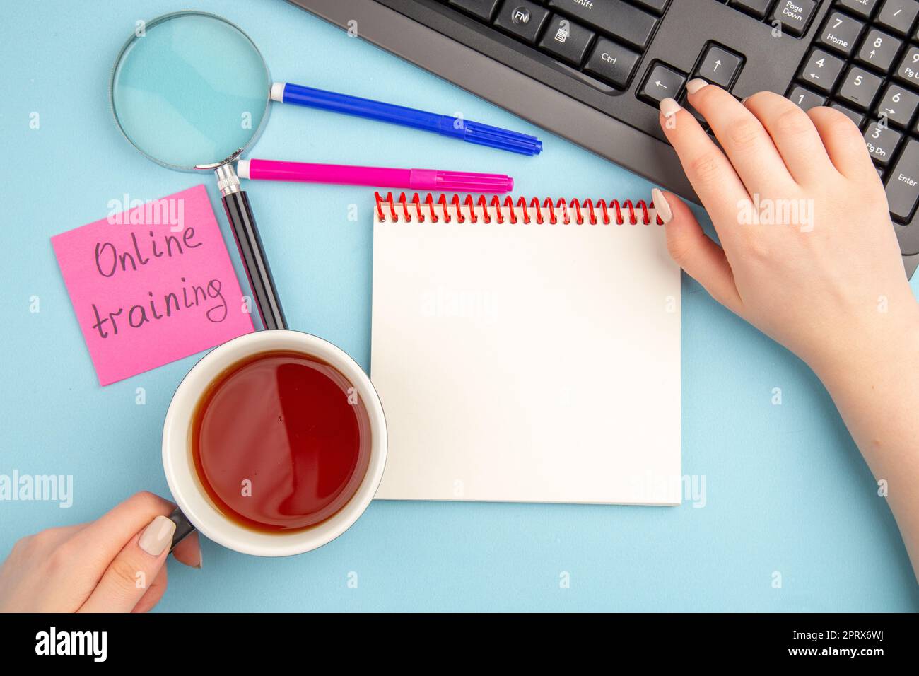 top view online training written on sticky note notepad cup of tea in ...