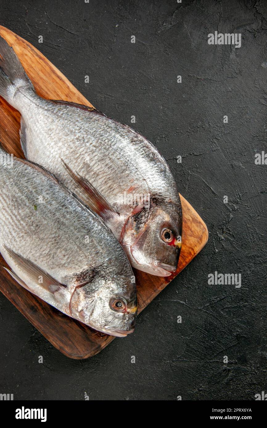 top view raw sea fish on chopping board on black background Stock Photo ...