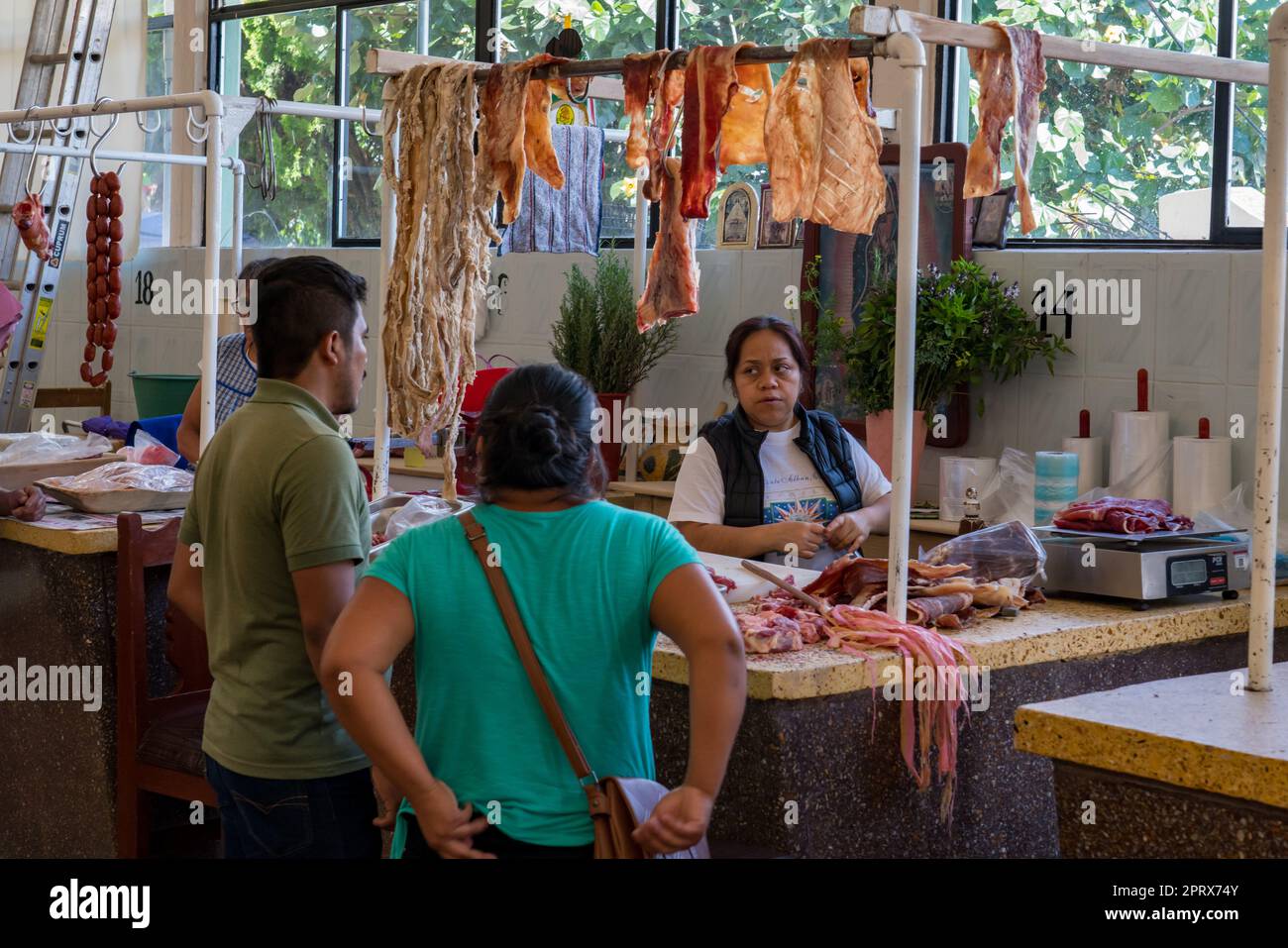 Shoppers buy meat at a butcher's stall in the market at Villa de Etla ...