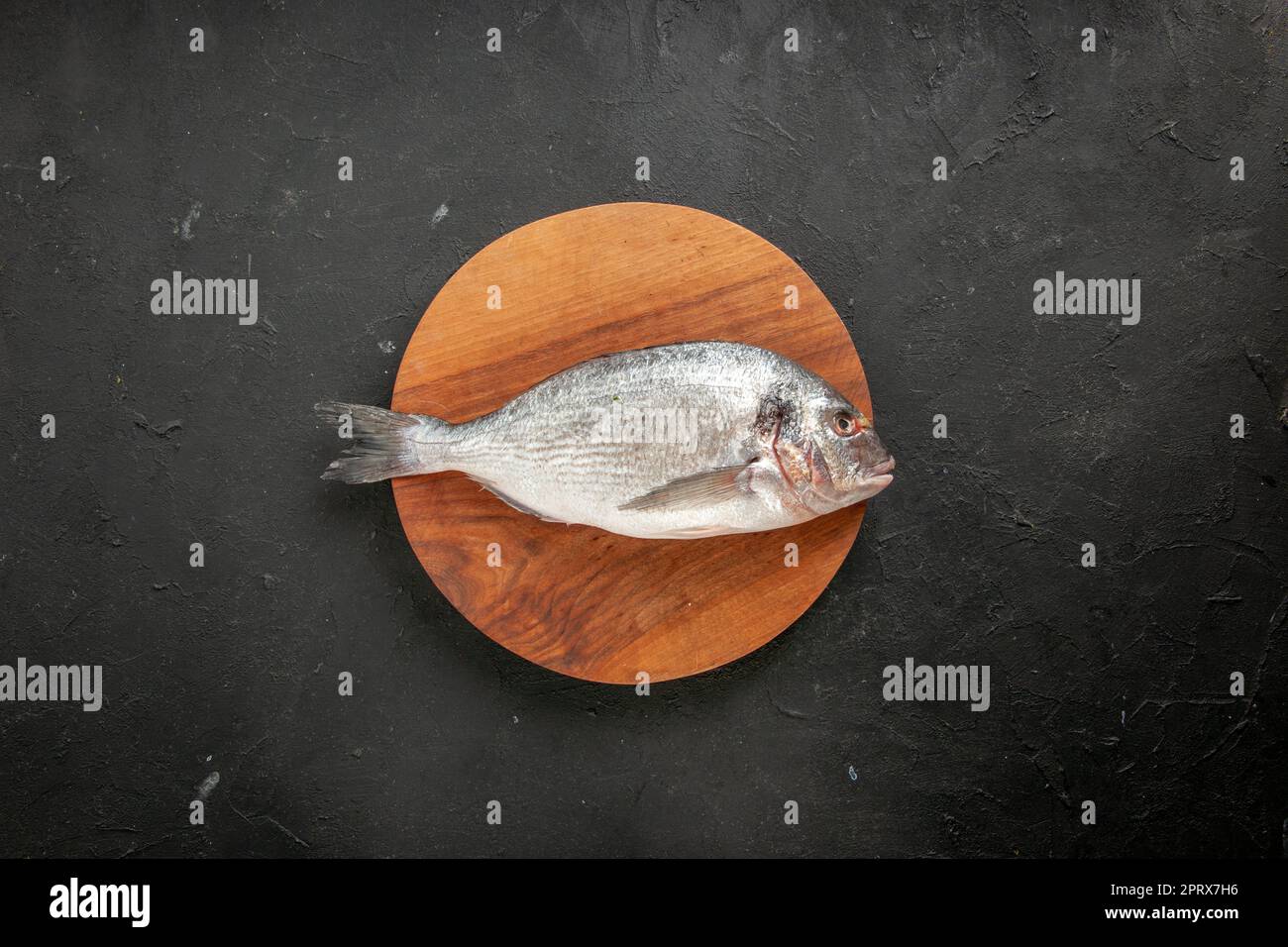 top view raw sea fish on wood board on black background with copy place ...