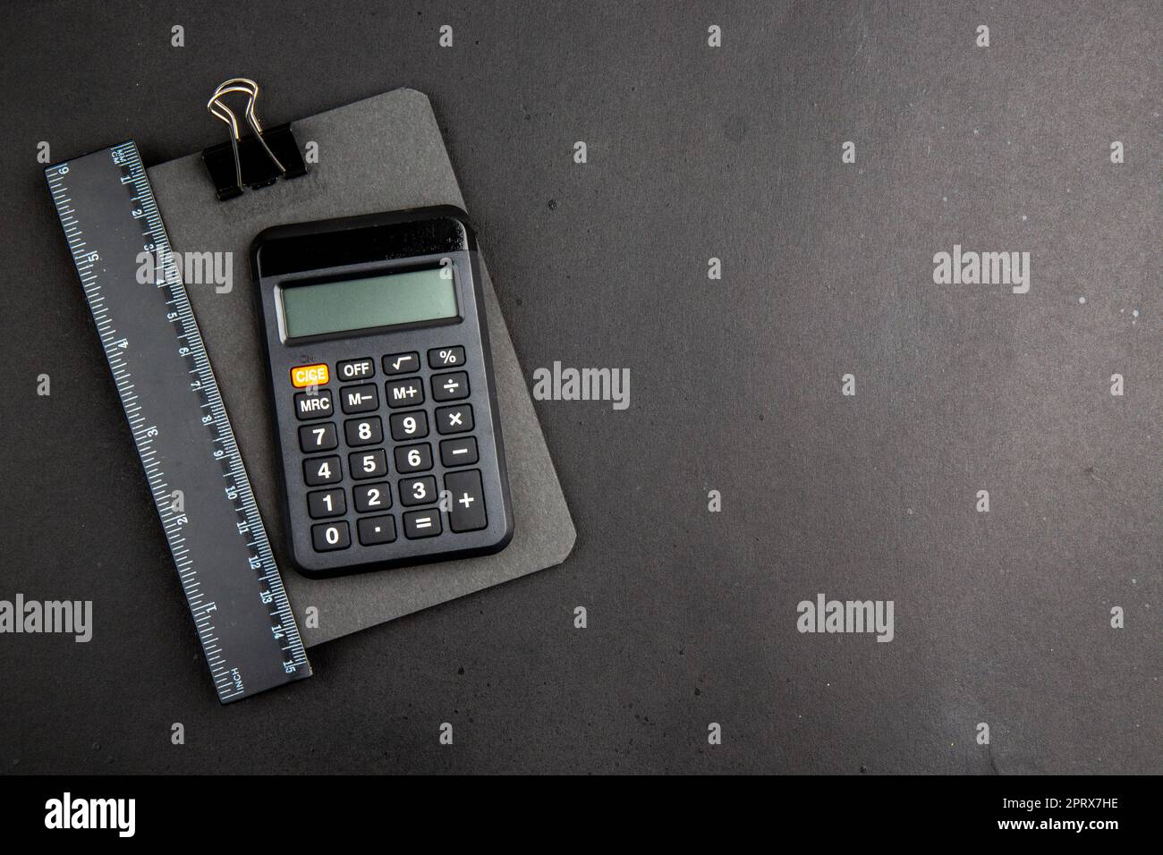 top view ruler and calculator binder clip on notepad on dark background ...