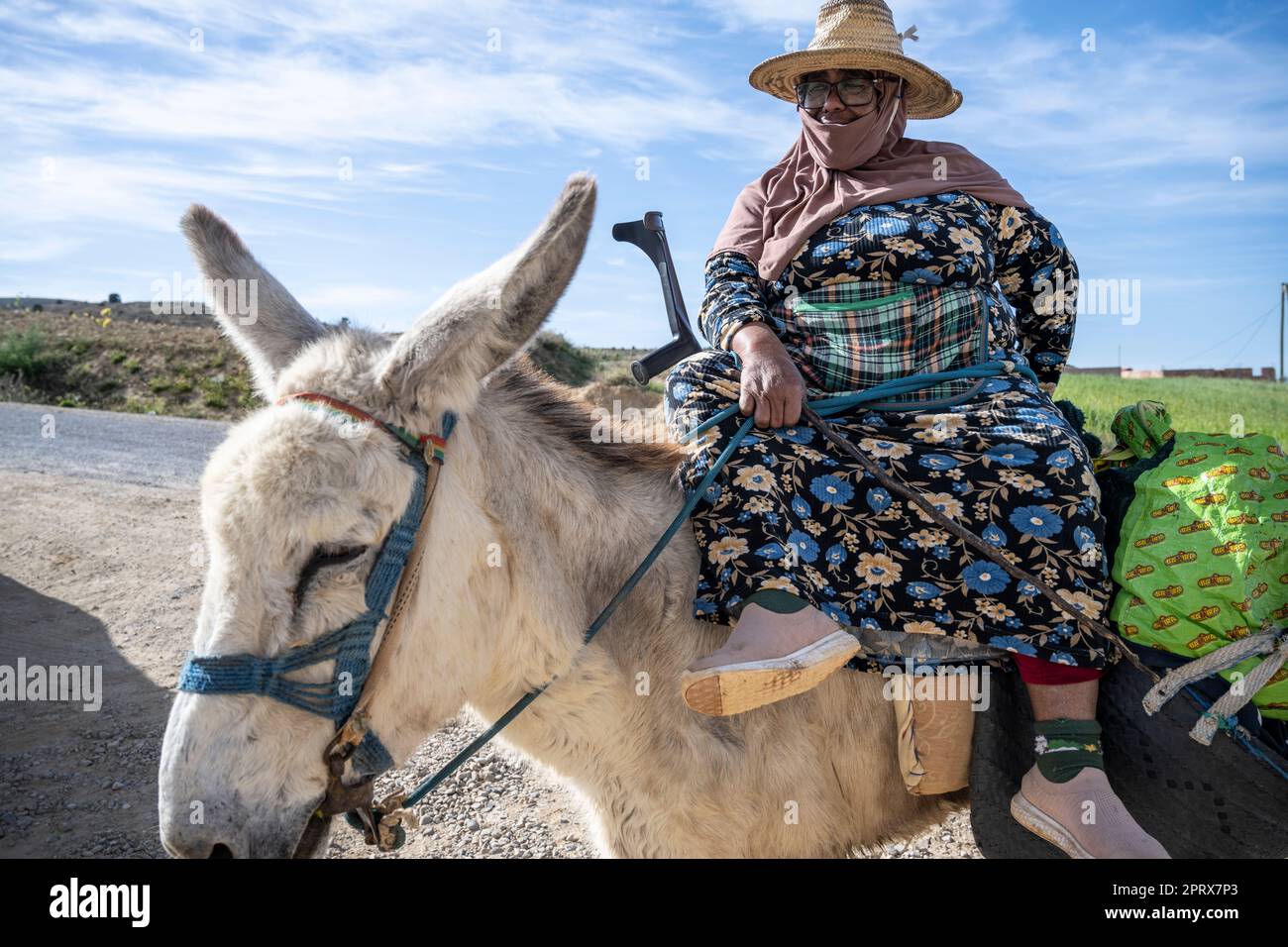 Woman with a straw hat and crutches riding a mule Stock Photo - Alamy