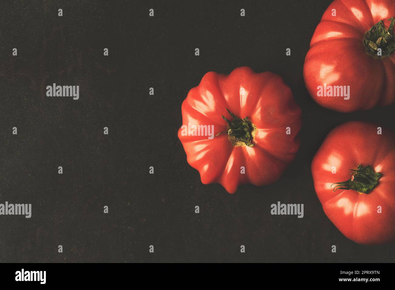 Fresh organic red tomatoes on rustic black metal kitchen countertop ...