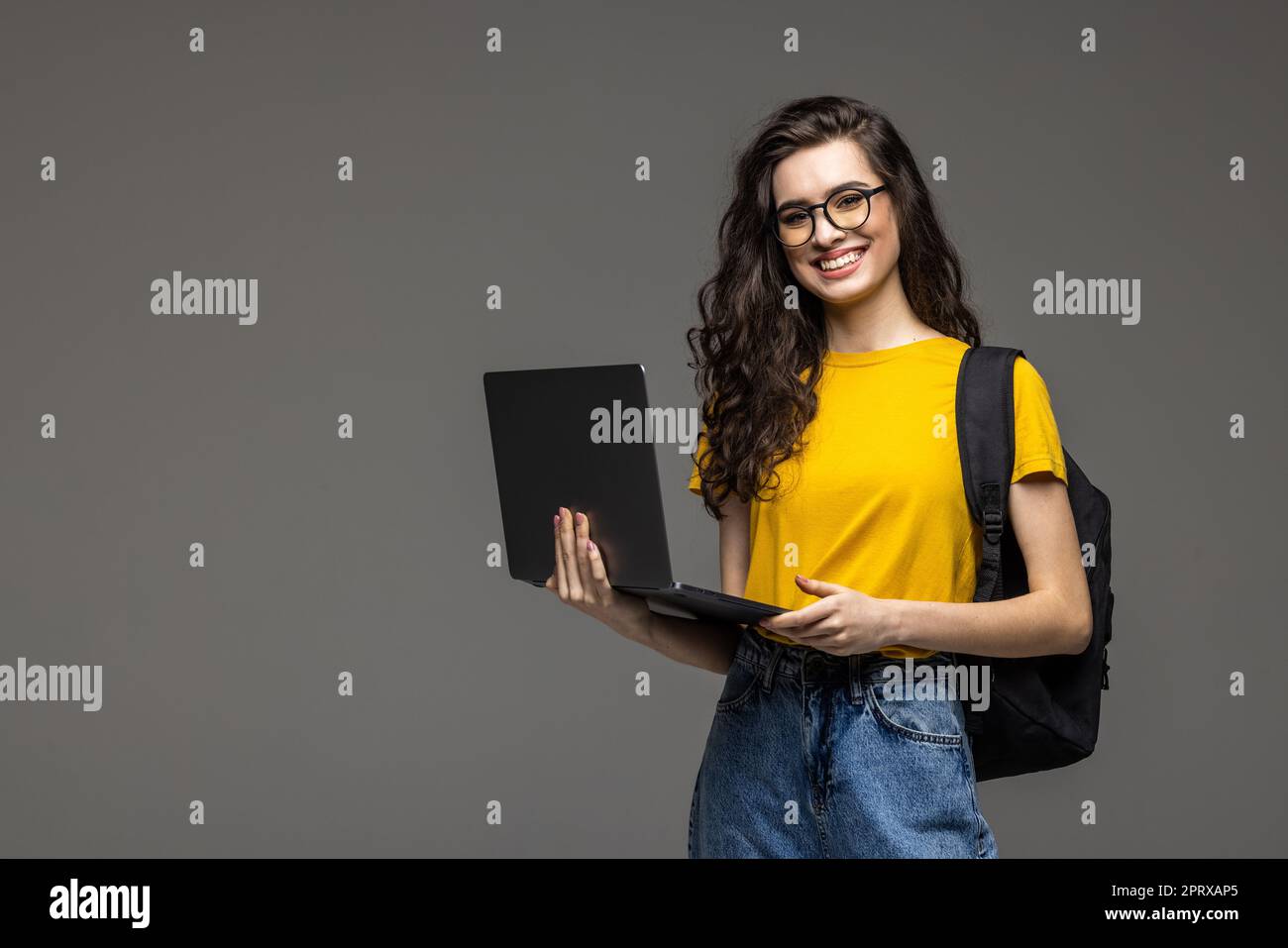 College student girl isolated on gray background, smiling at camera ...