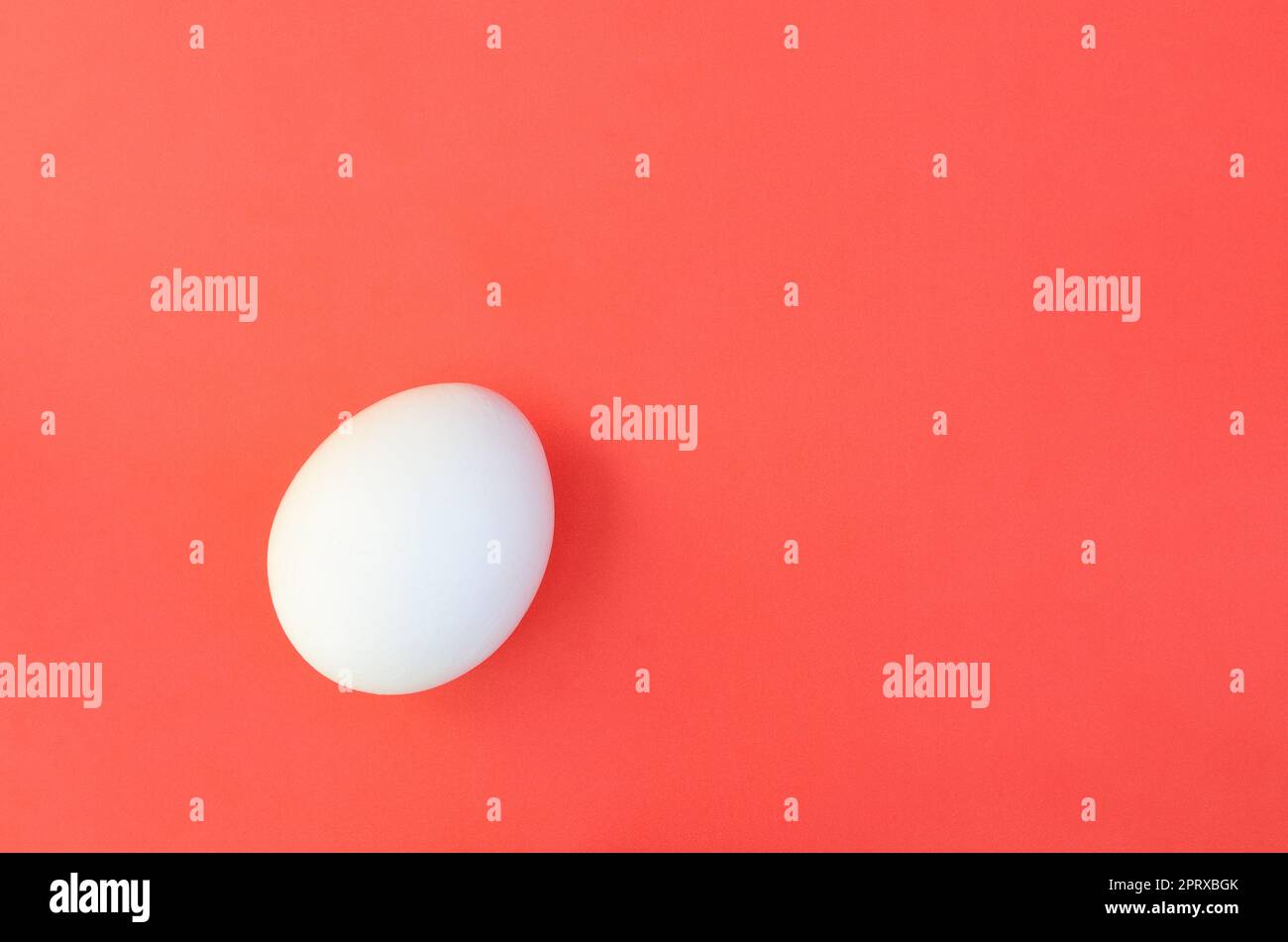 One white egg on a bright red background Stock Photo - Alamy