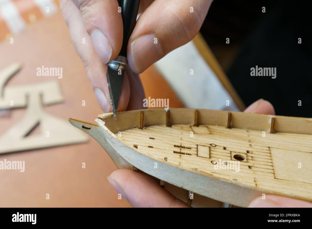 Hands of man cutting out details for ship model with clerical knife ...
