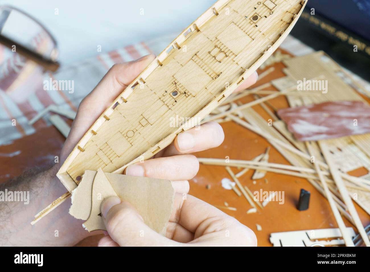 Hands of man adjusts plywood details for ship model, grinding on ...