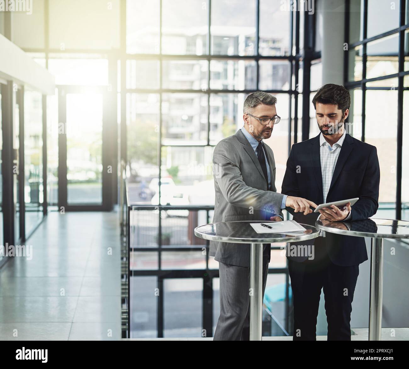 Lets move forward on this. two businessmen looking over a tablet in the ...