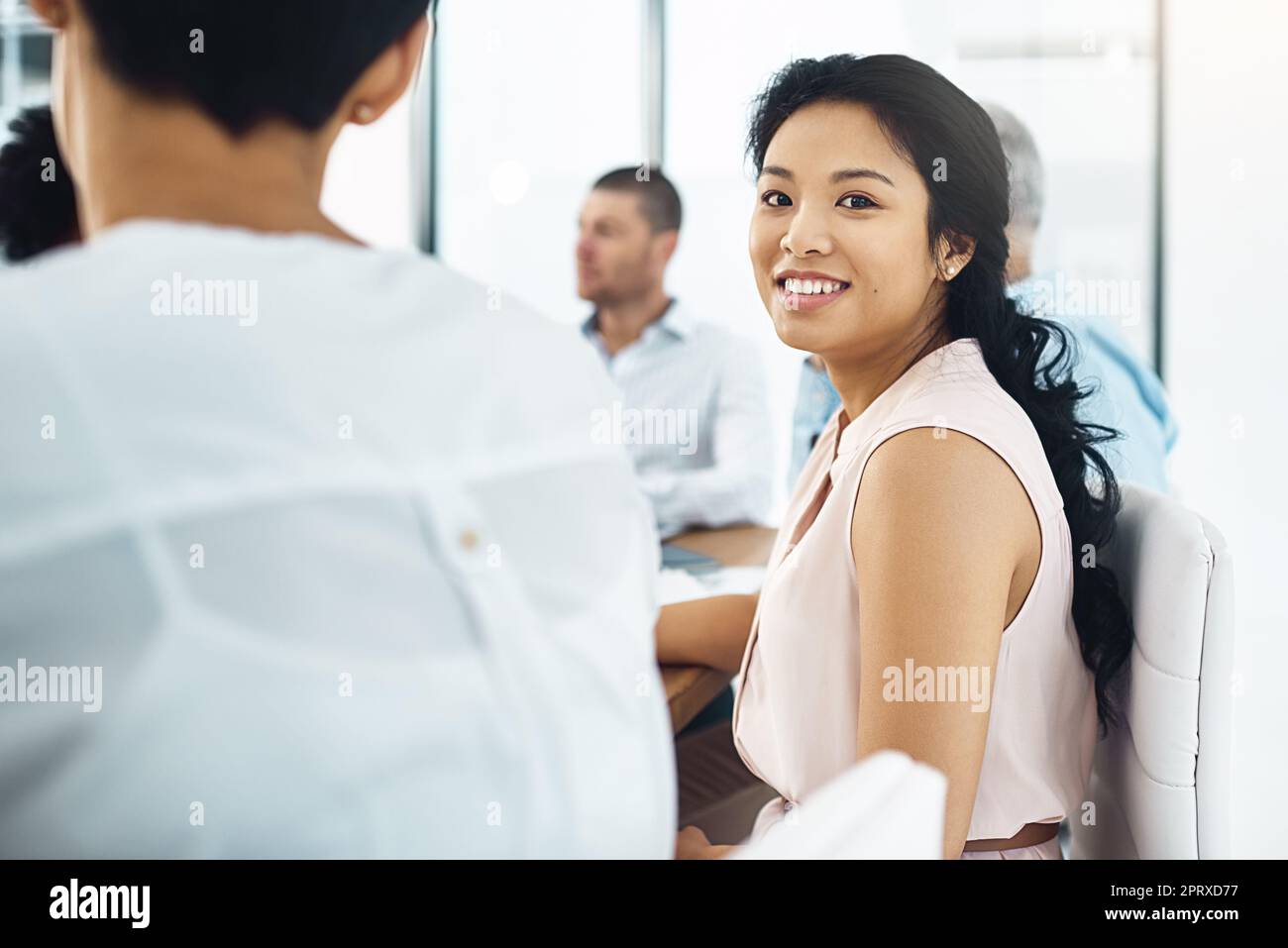 All set and ready for success. Portrait of a young businesswoman sitting in a meeting alongside ...